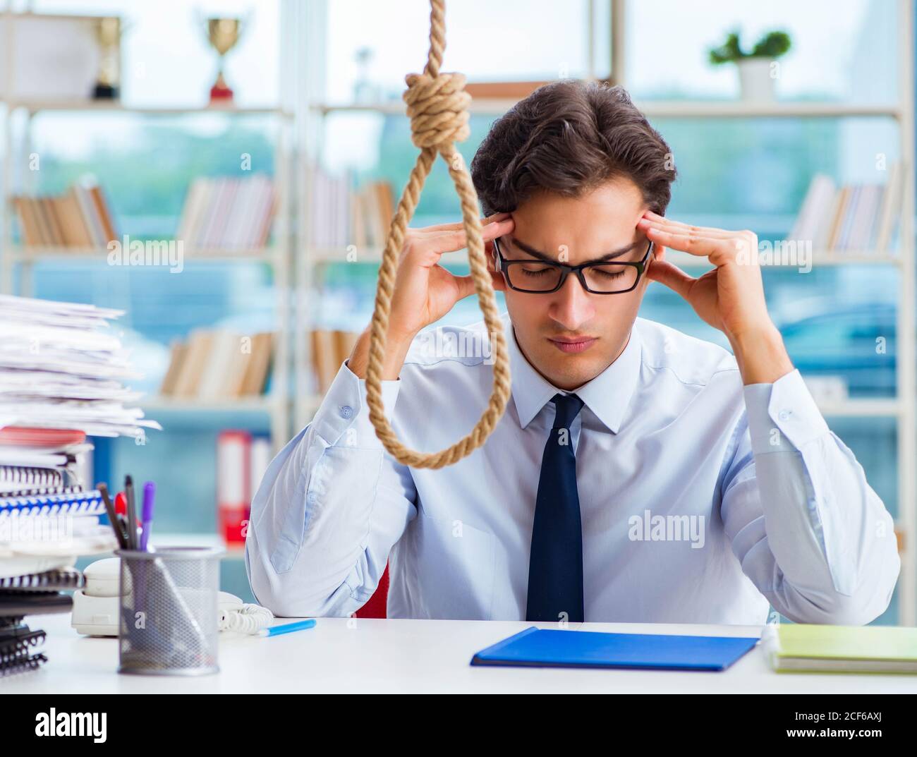 The unhappy businessman thinking of hanging himself in the office Stock ...