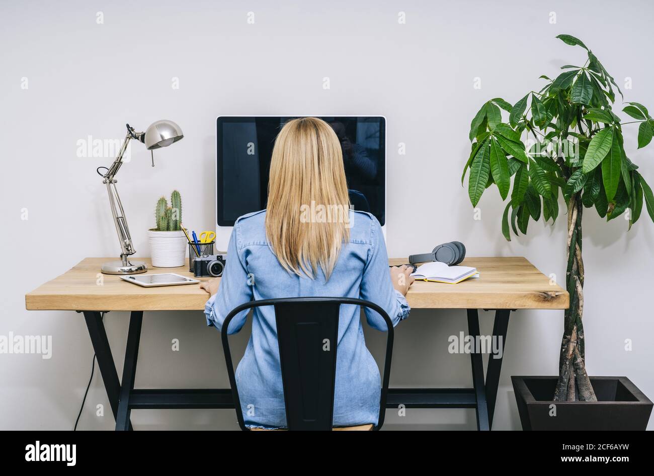 Back view o blonde caucasian Woman in casual clothes sitting on wooden ...