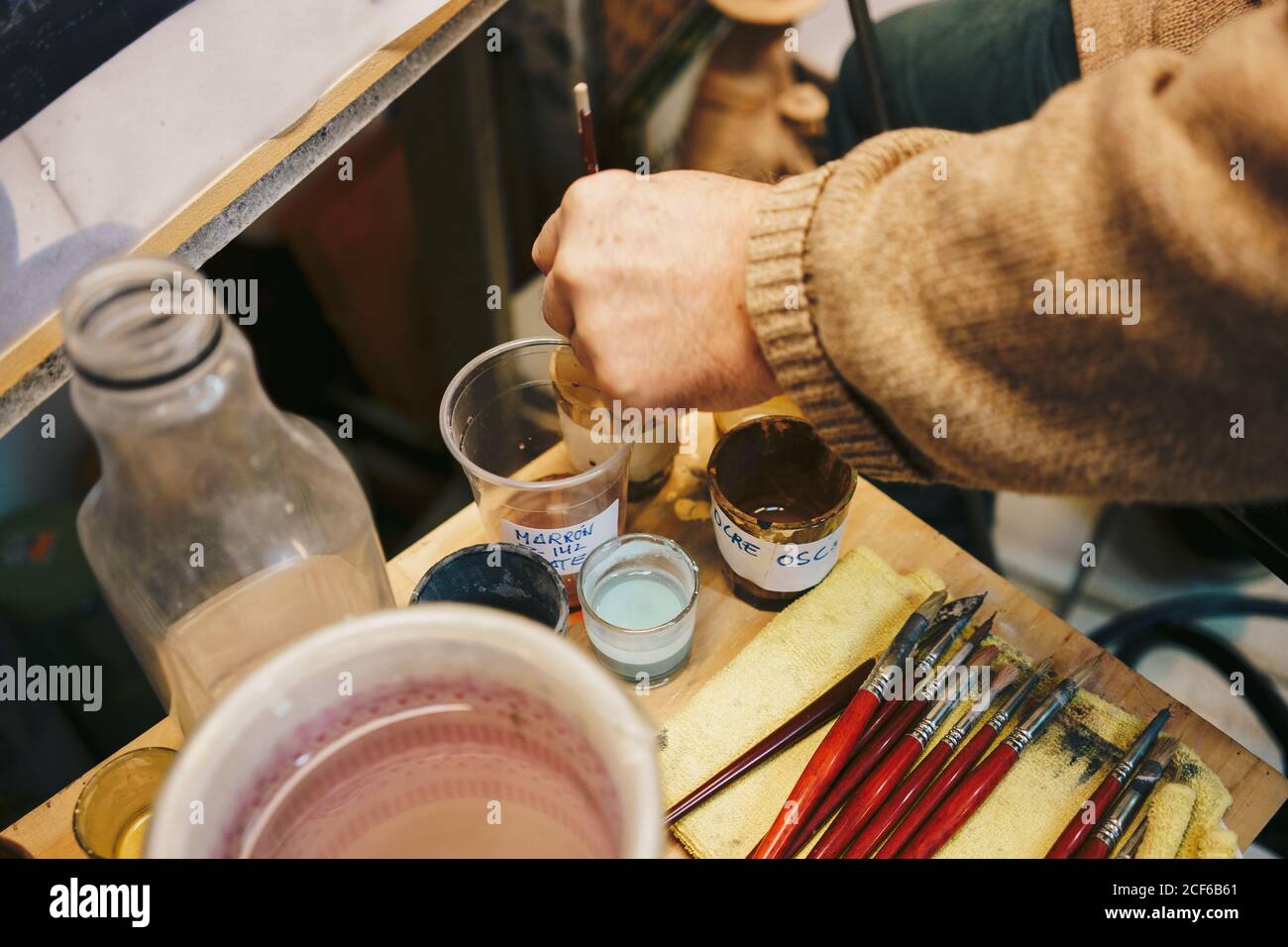Person taking paint with brush from glass having drawing tools around ...