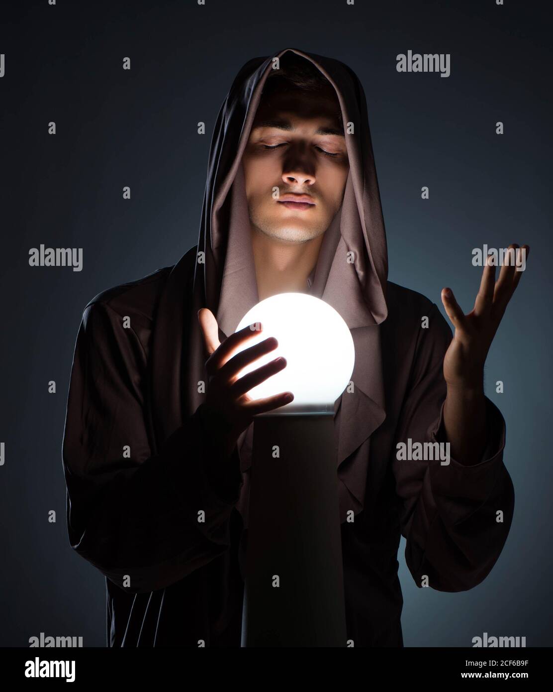 The young wizard with crystal ball in dark room Stock Photo - Alamy