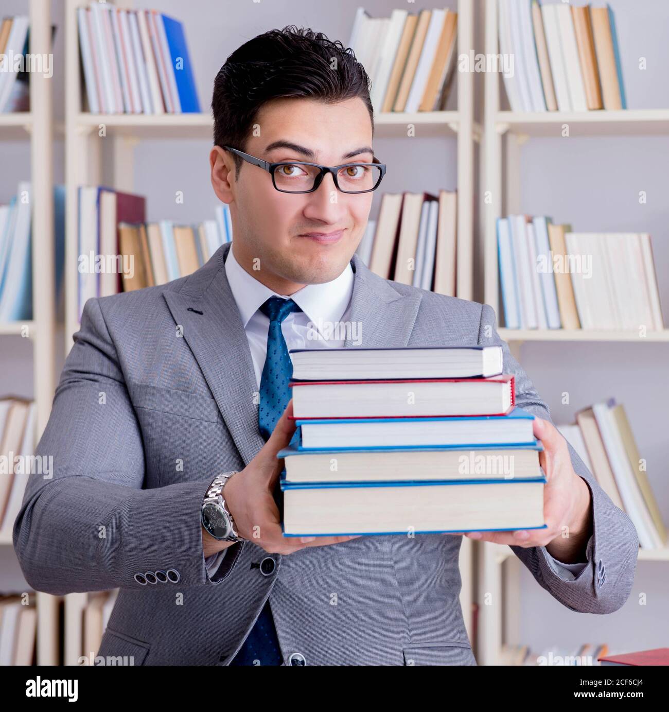 Business law student with pile of books working in library Stock Photo ...