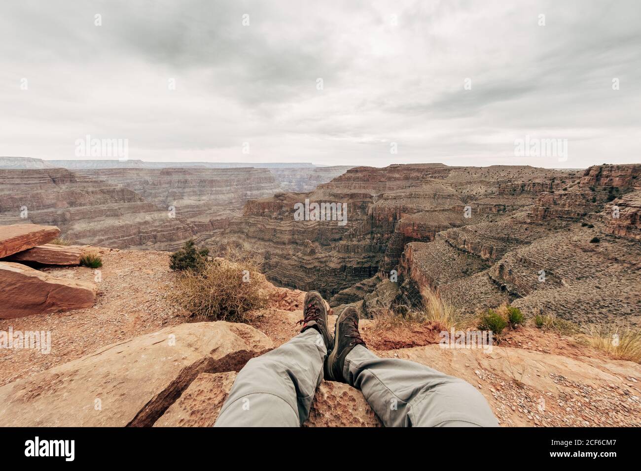 Crop tired man in sportswear relaxing on edge of cliff at picturesque ...