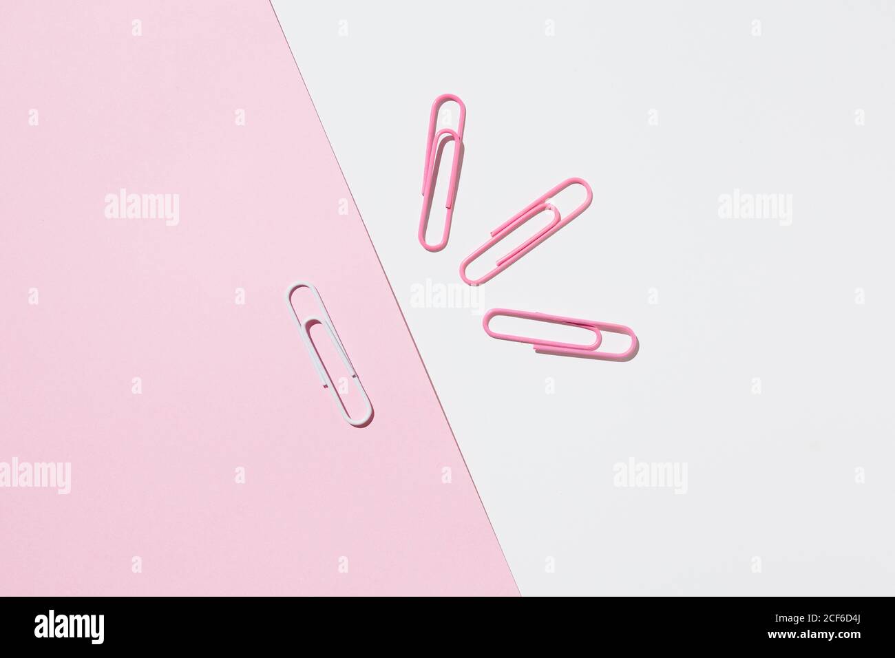 Top view of white and pink paper clips arranged on colorful background ...