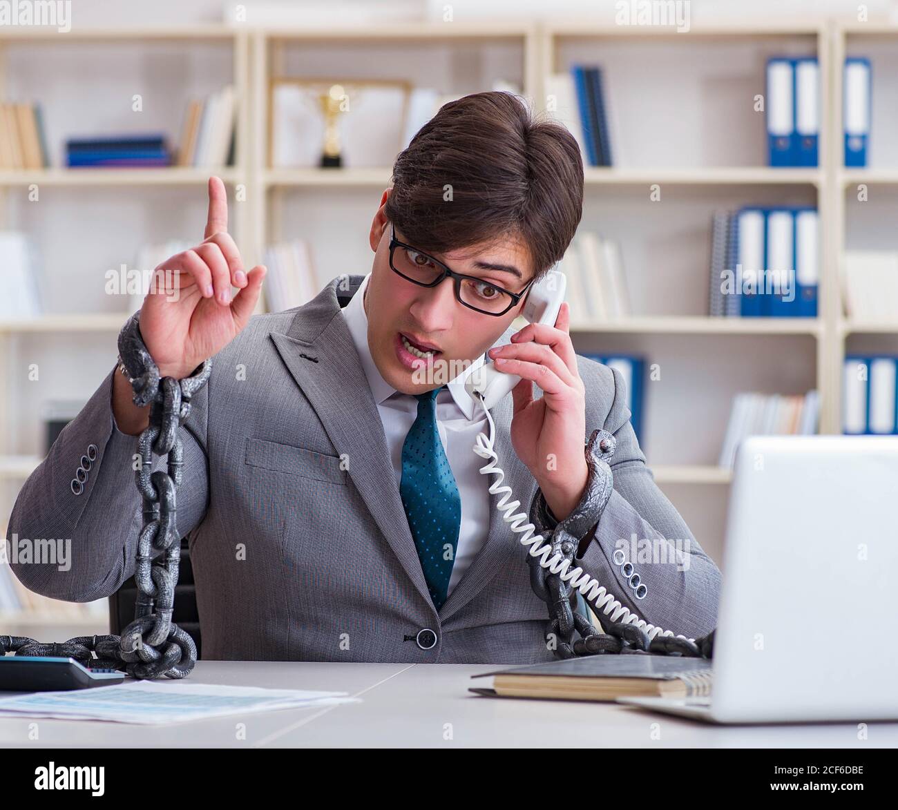 Businessman tied with chains to his work Stock Photo - Alamy