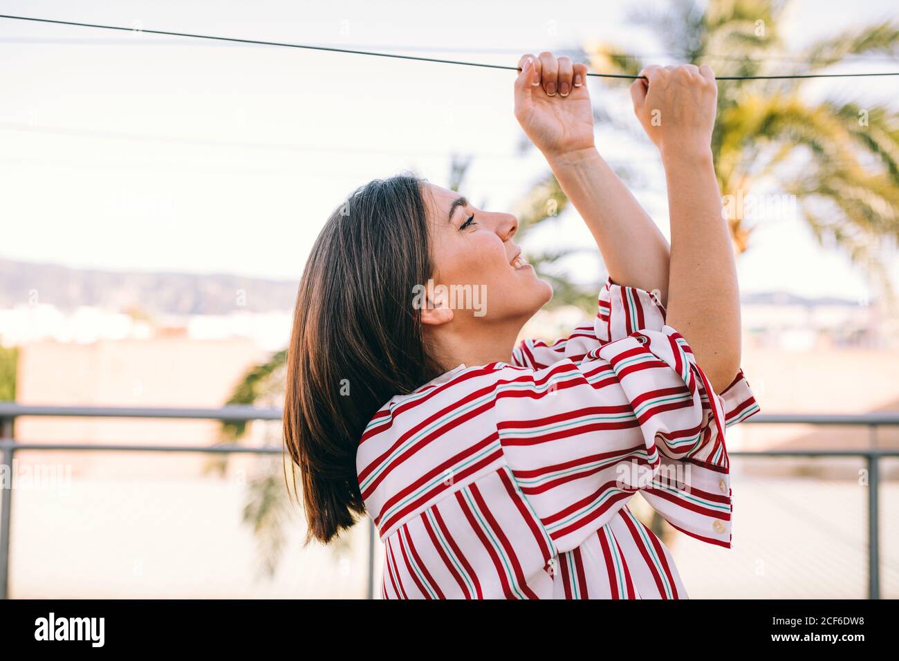 Side view of playful female wearing stylish clothes holding rope on ...