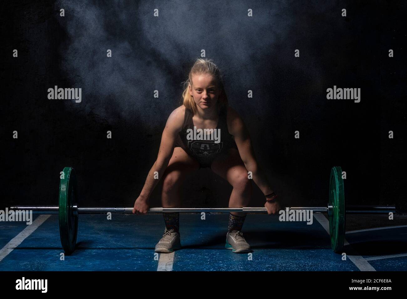 Happy muscular Woman win sportswear smiling and lifting heavy barbell ...