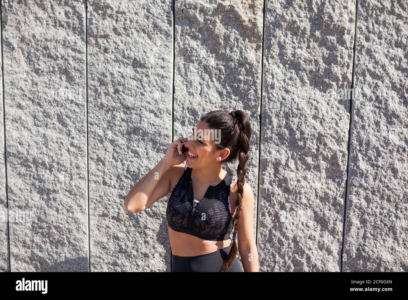 beautiful and brunette Woman leaning against a granite wall while ...