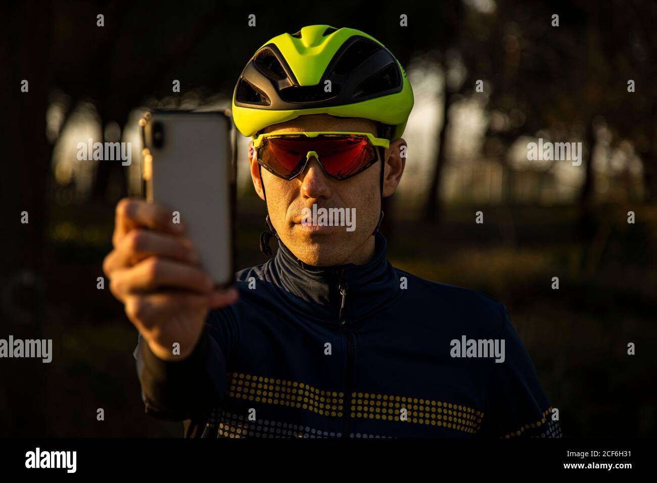 man cyclist resting while using mobile phone to take a picture on the ...