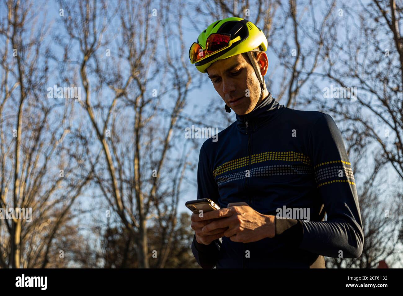 man cyclist resting while using mobile phone on the bike lane in a park ...