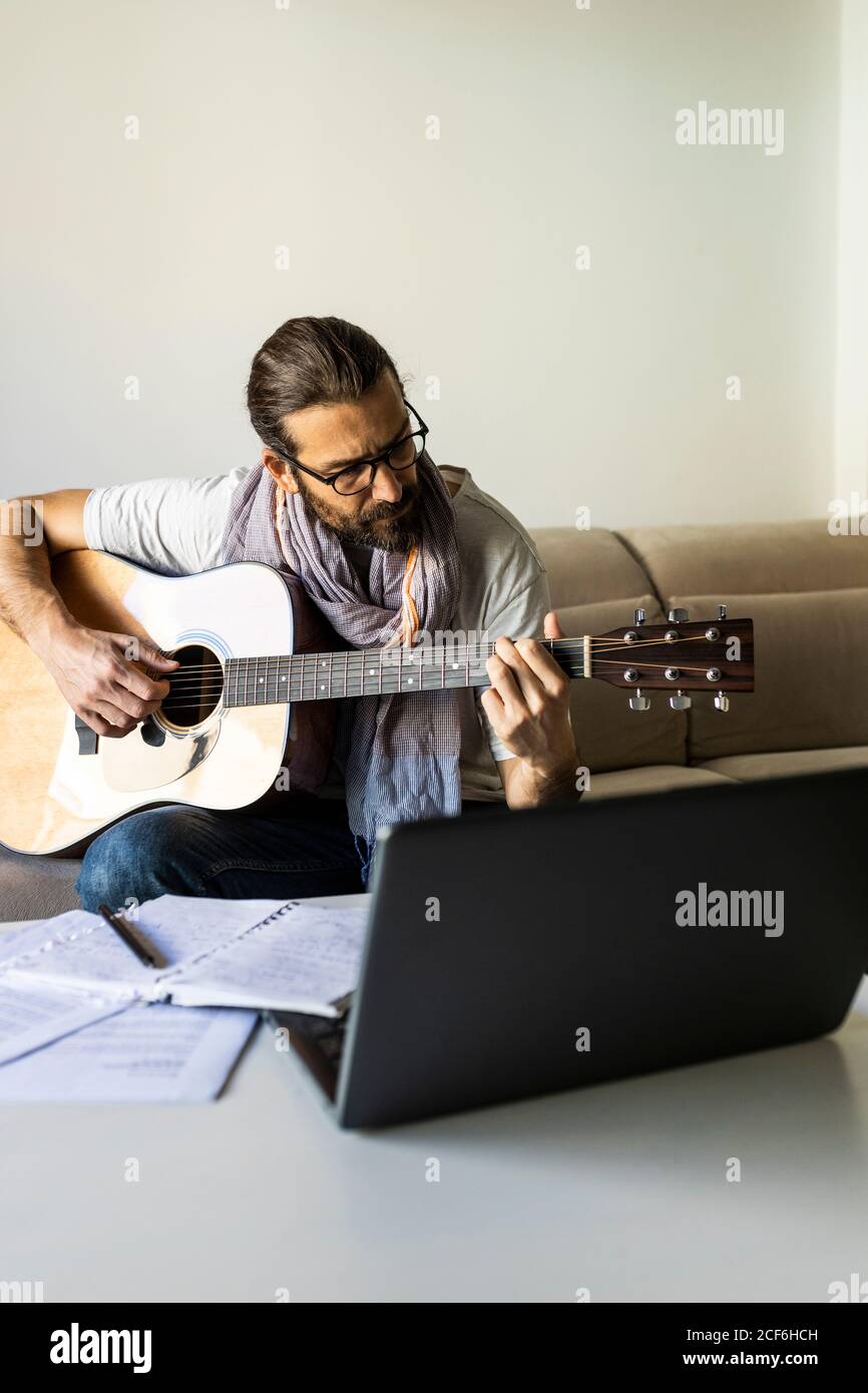 Stylish guitarist on couch in living room Stock Photo - Alamy
