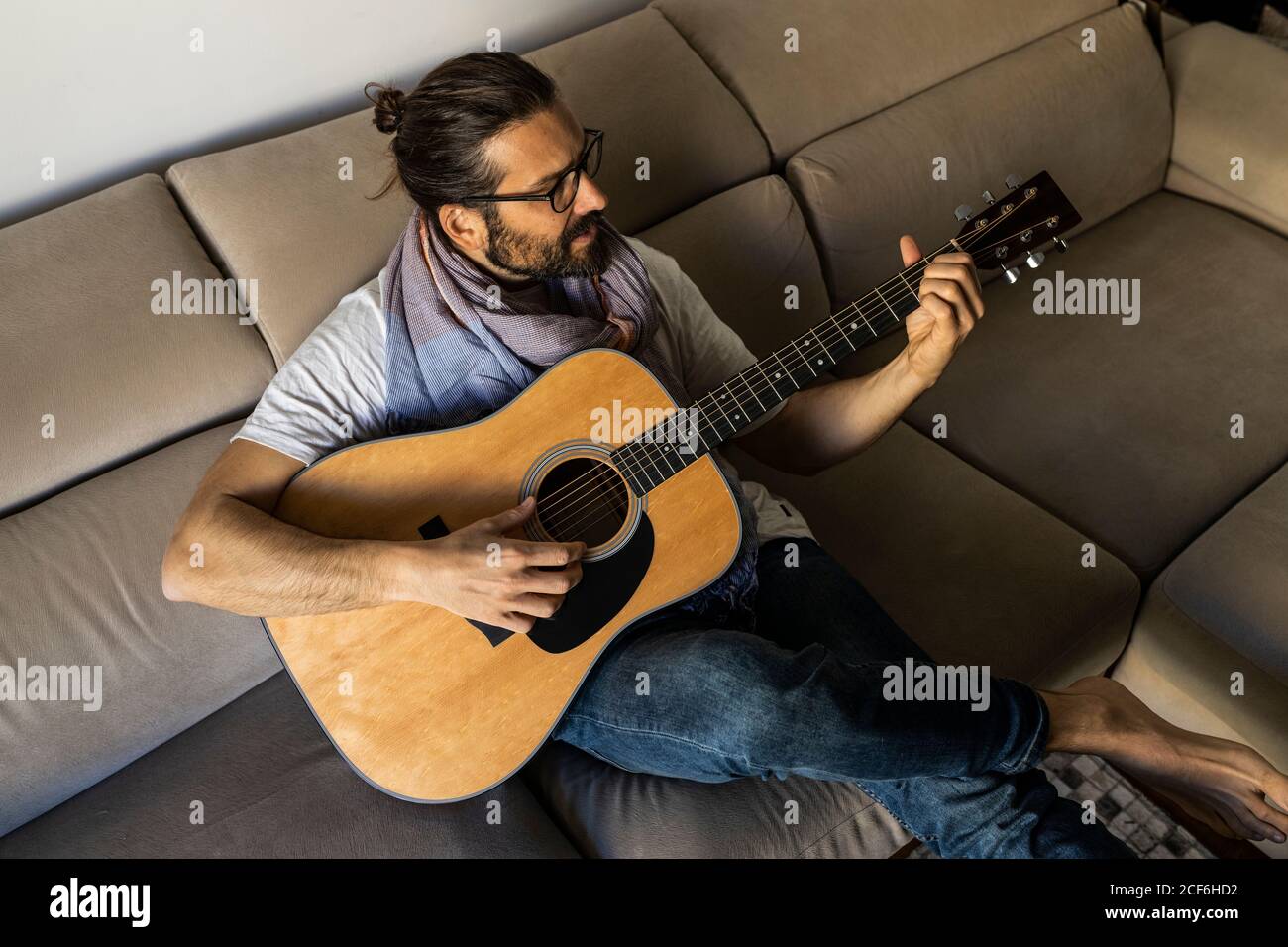 Stylish guitarist on couch in living room Stock Photo - Alamy