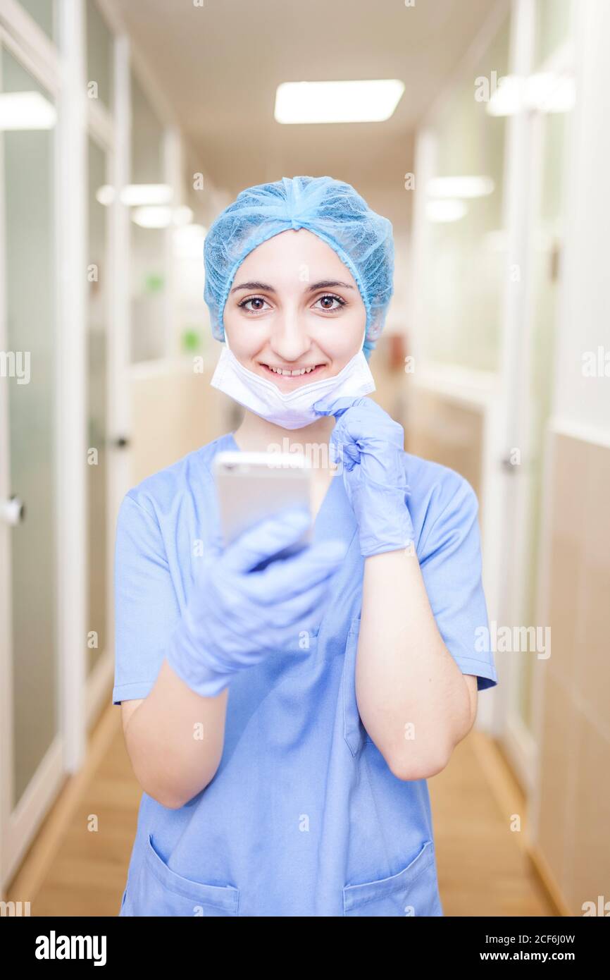 female surgeon standing in the hallway while checking messages on her ...