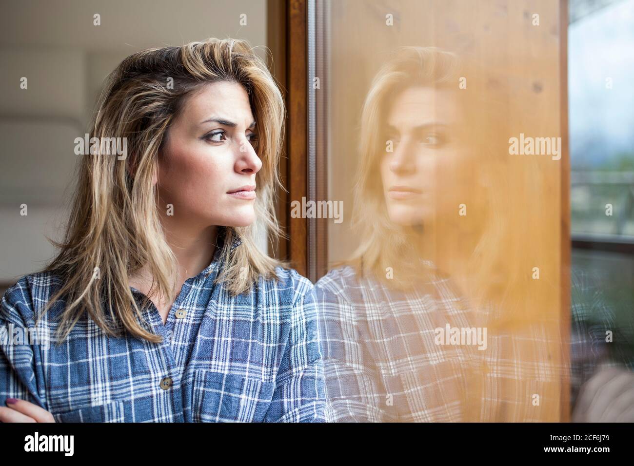 Beautiful and young Woman looking out the window of her house Stock ...