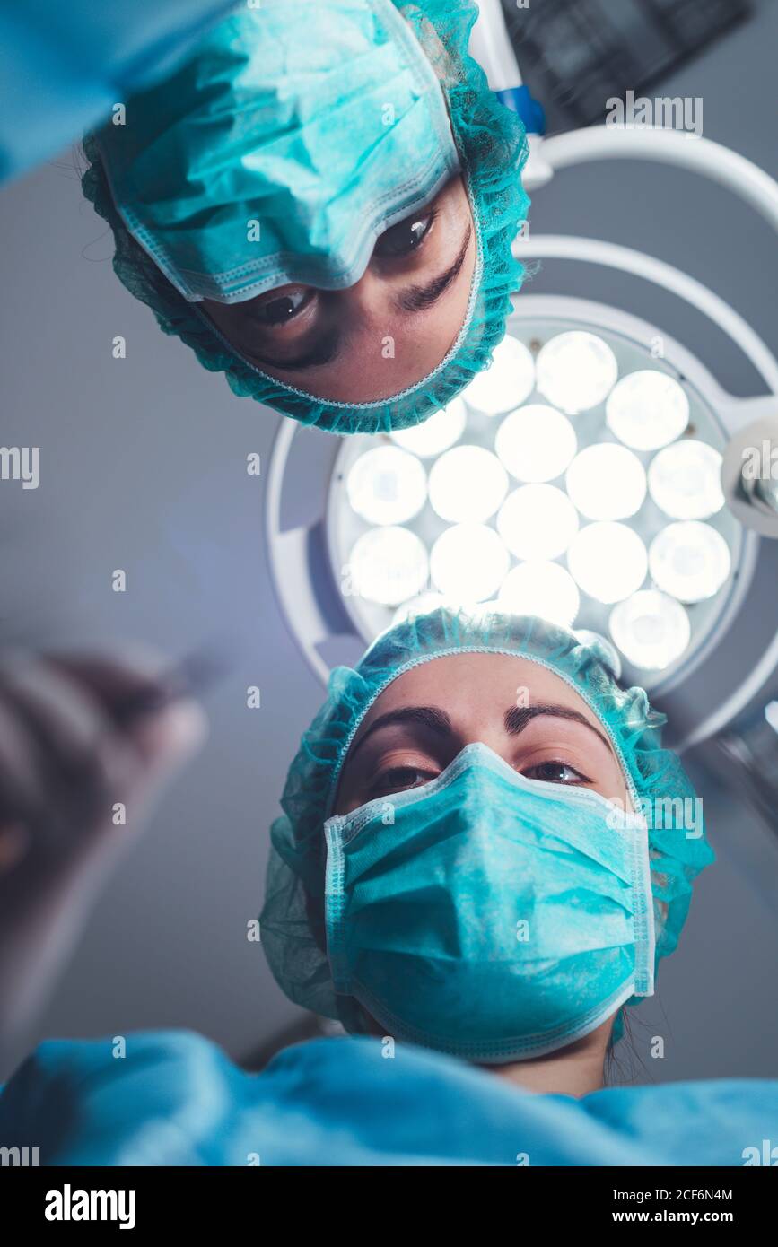 From below female surgeons in medical uniform using professional tools ...