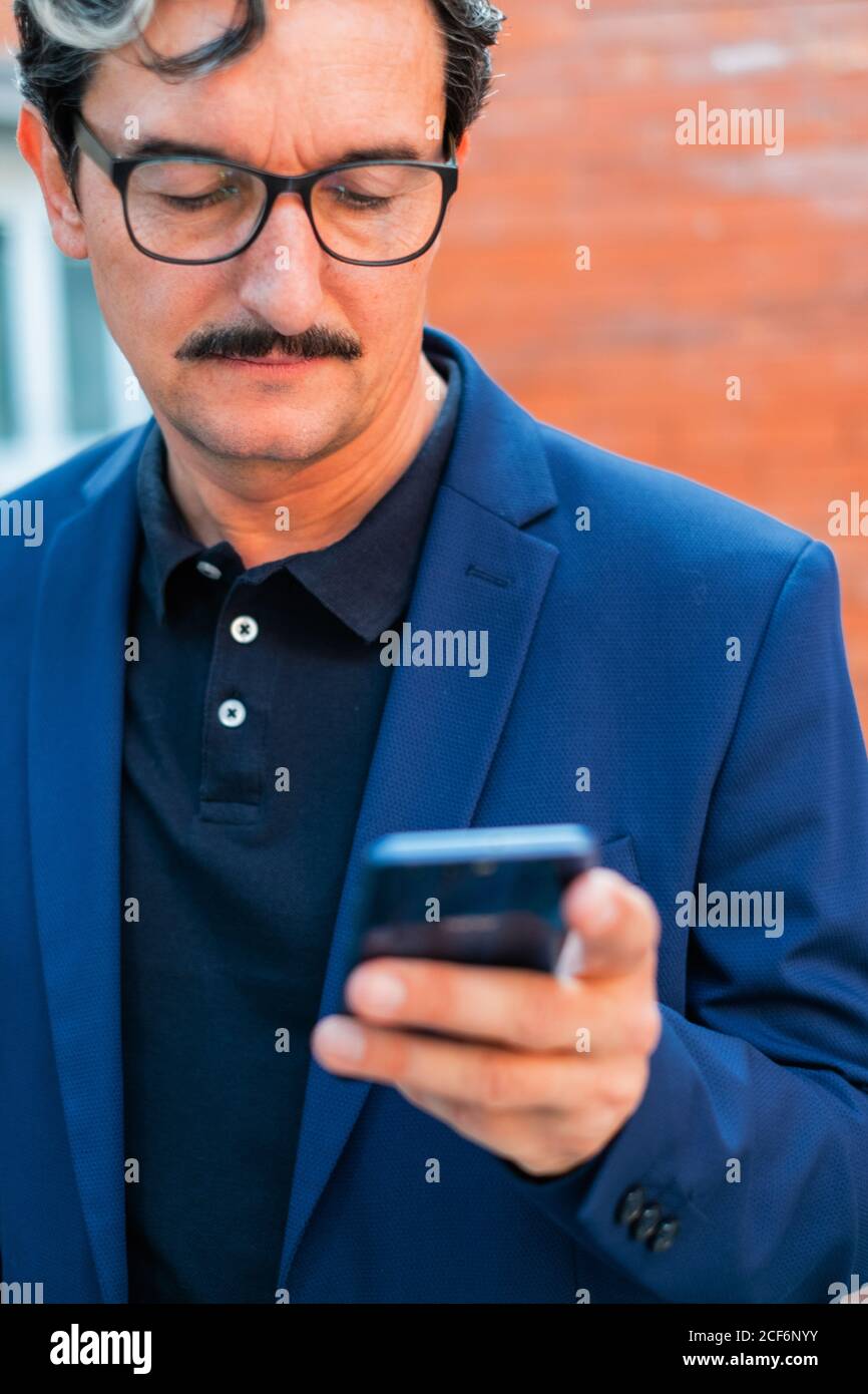 Concentrated aged male office worker with mustache in formal wear ...