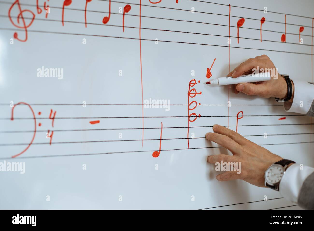 unrecognizable man hands writing music notes in a white board at a ...