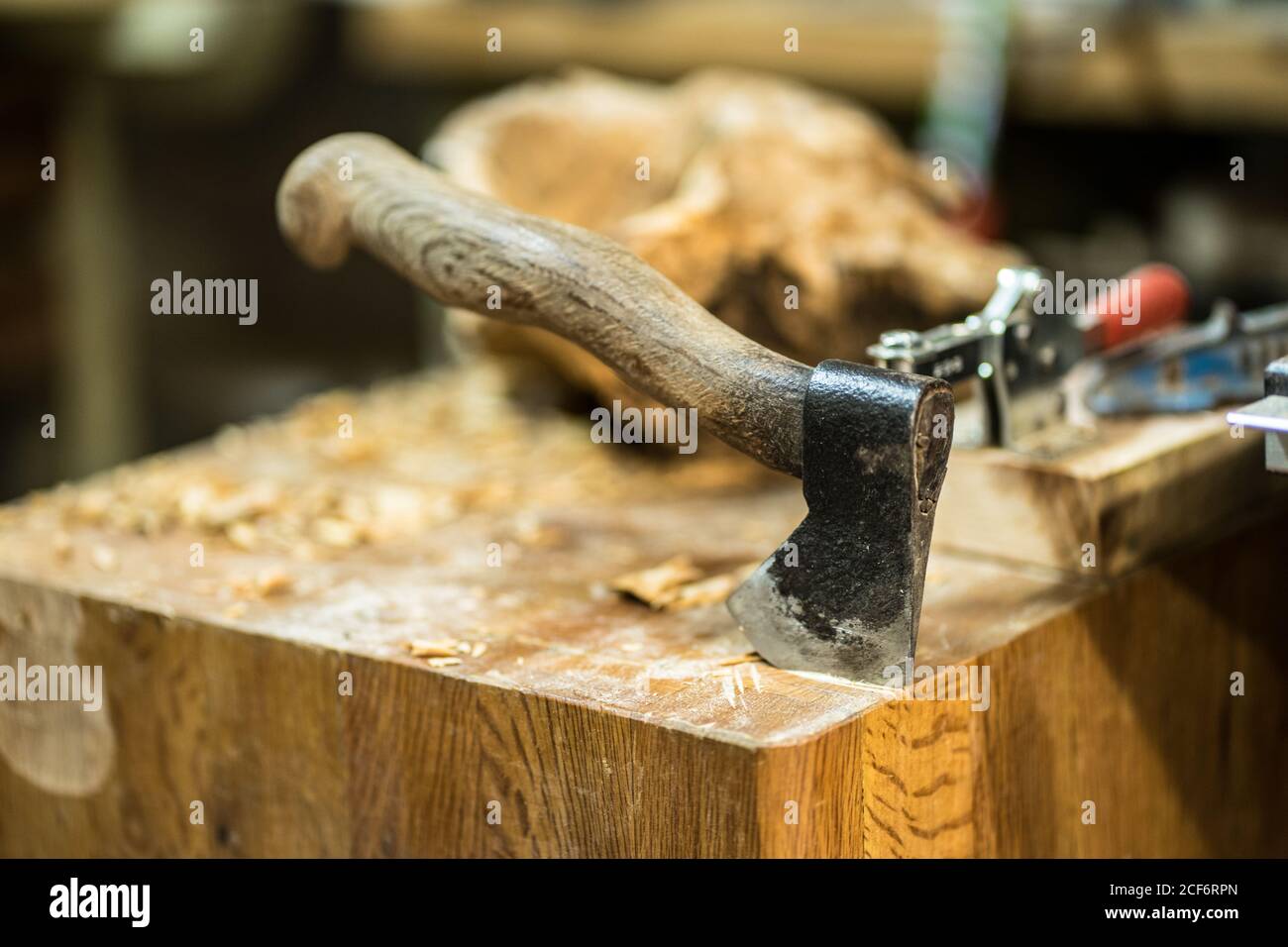 Shabby axe with wooden handle sticking out of large square wooden table ...