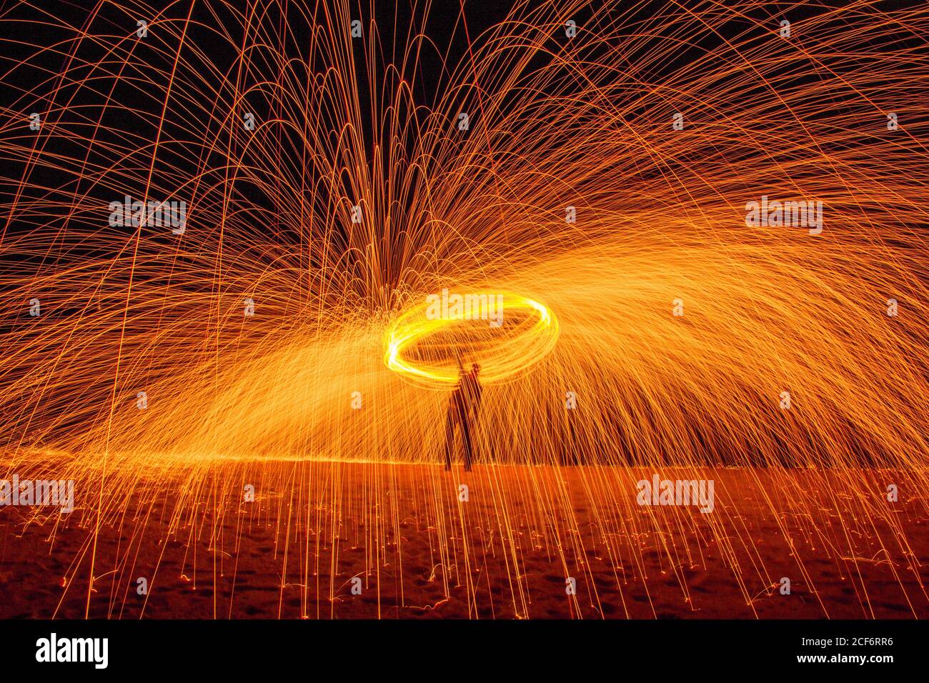 Long exposure silhouette of unrecognizable person spinning burning ...