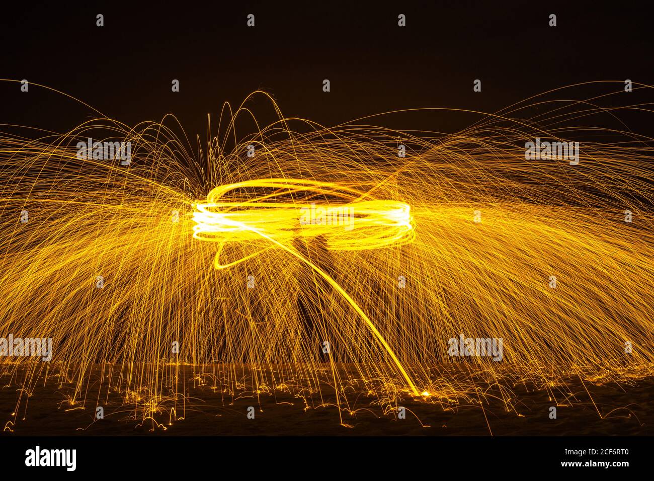 Long exposure silhouette of unrecognizable person spinning burning ...