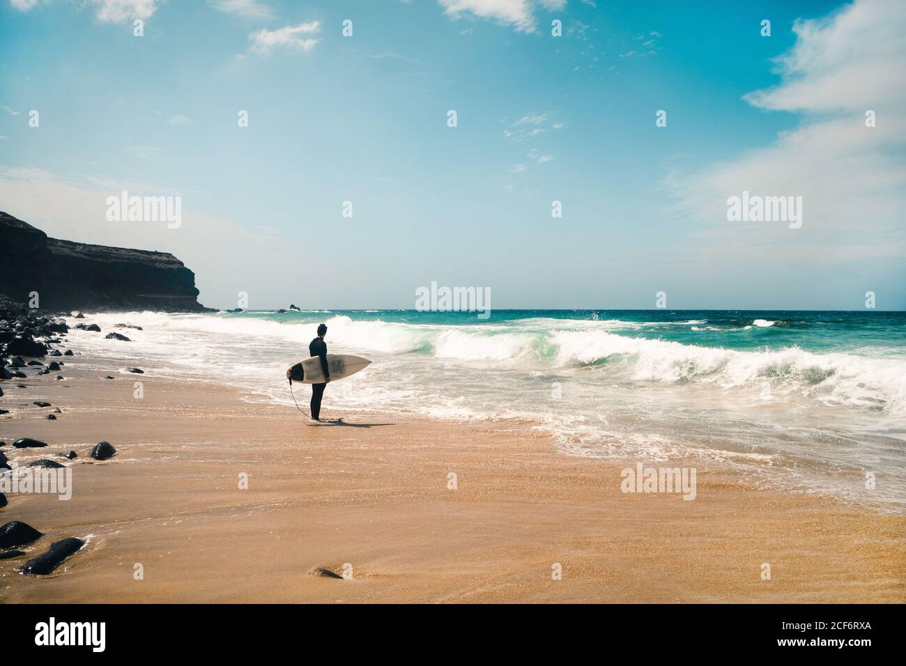 Full body anonymous man with surfboard standing on sandy beach near ...