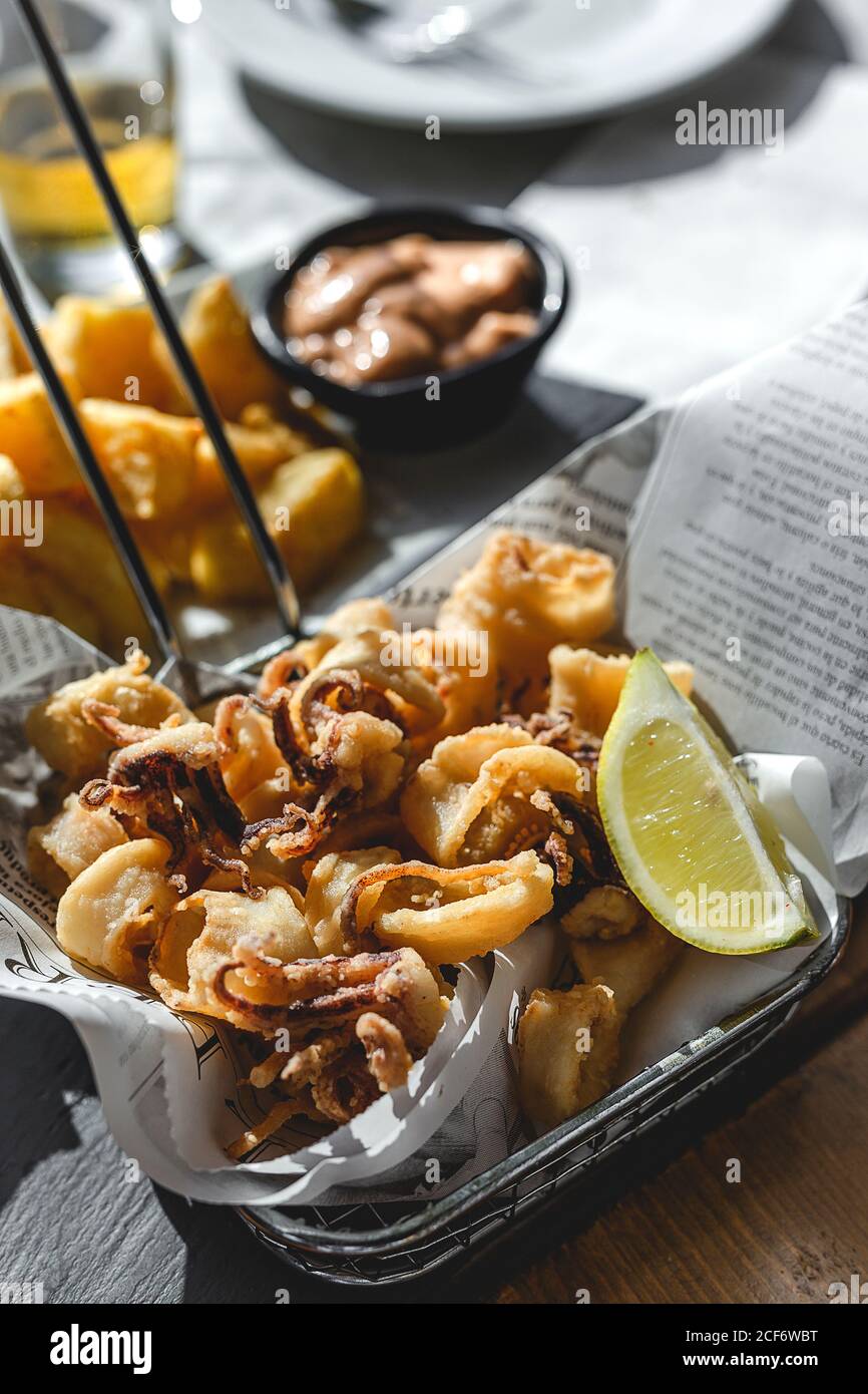 From above of fried small octopuses served in fryer basket with slice ...