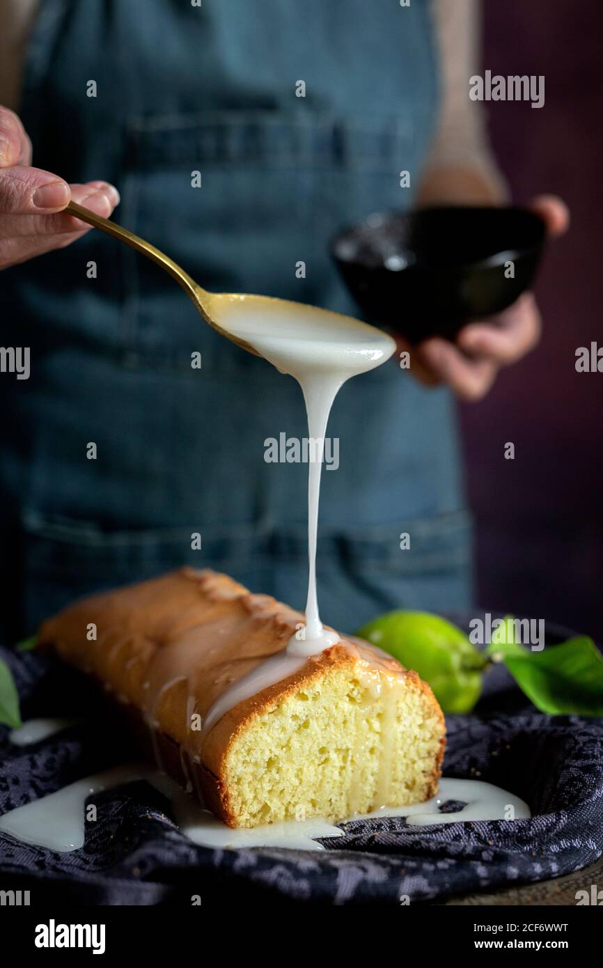From above cropped unrecognizable Woman hands pouring white sweet glaze ...