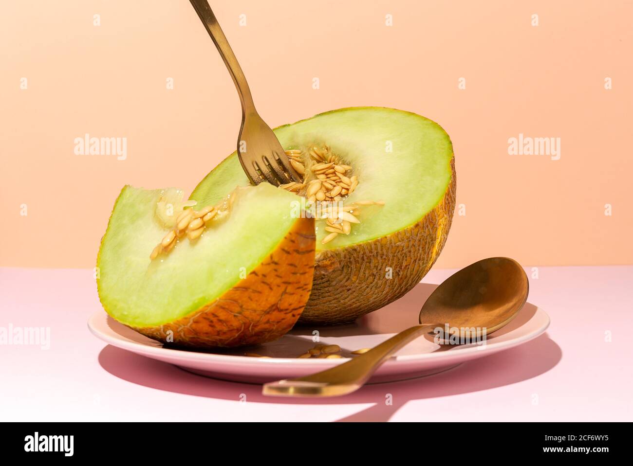 Cut ripe appetizing sweet pitted melon on plate with spoon and fork in ...