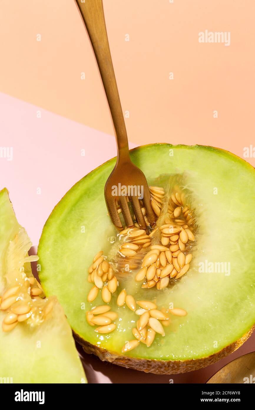 From above cut ripe appetizing sweet pitted melon on plate with spoon ...
