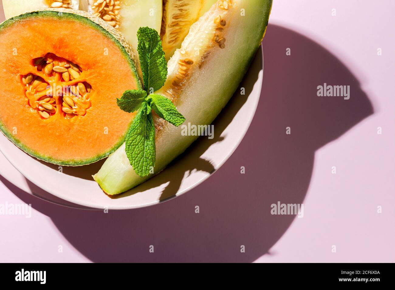 Fresh assortment melon with mint on pink background with high contrast ...