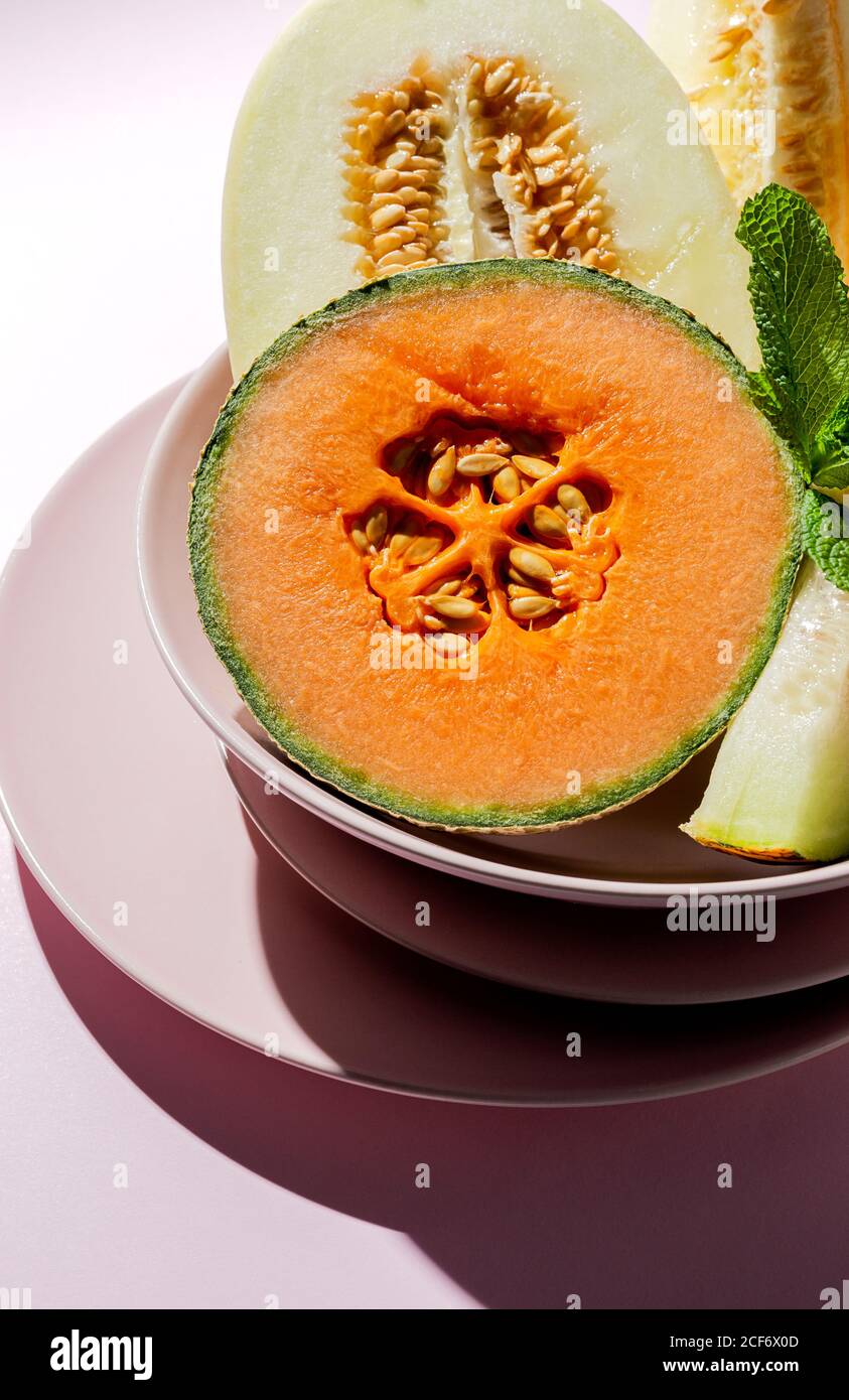 Fresh assortment melon with mint on pink background with high contrast ...