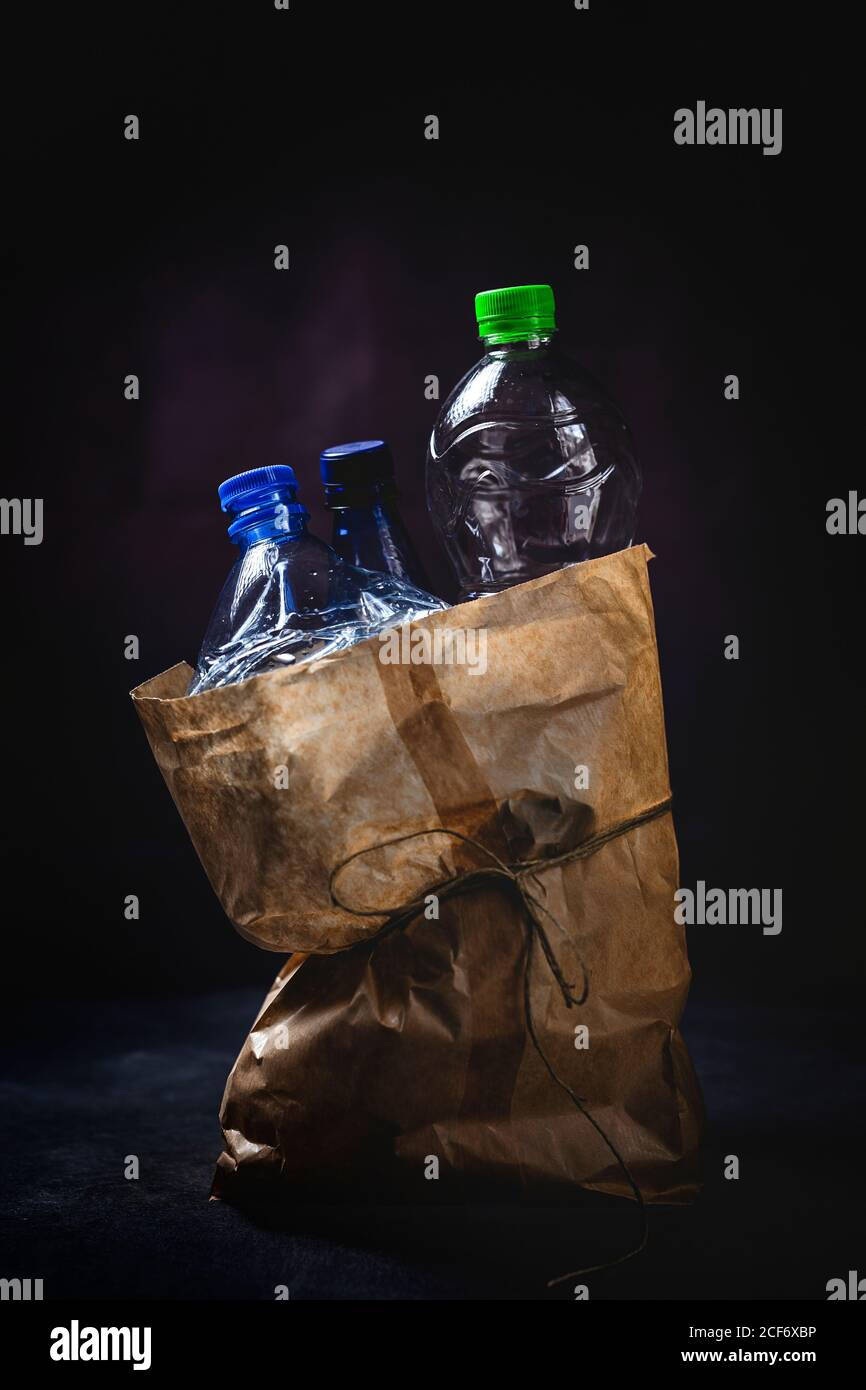 Dirty paper sack with discarded plastic bottles placed on black ...