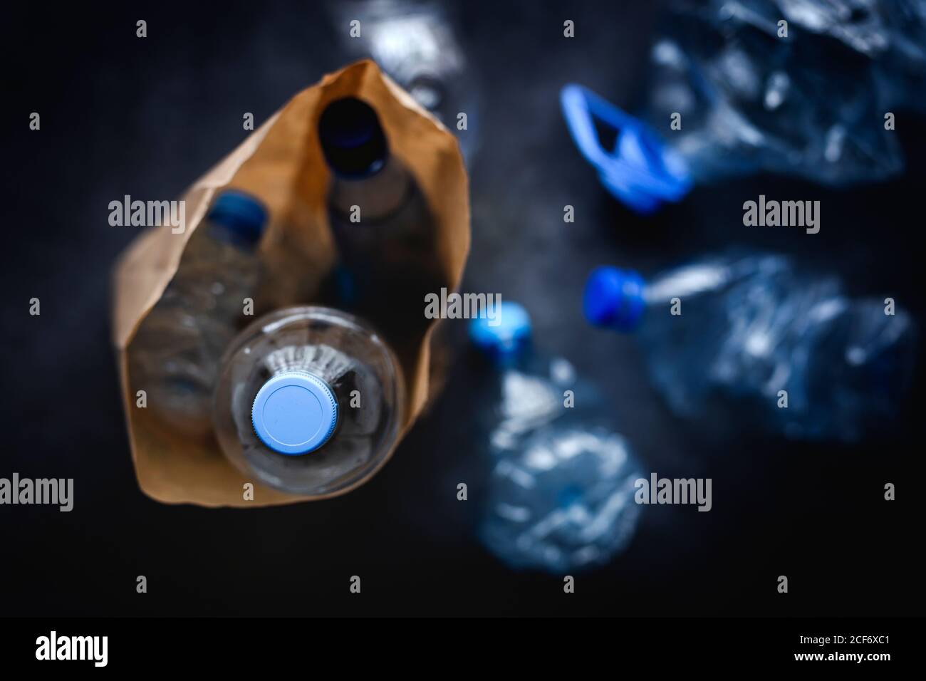 from above dirty paper sack with discarded plastic bottles placed on ...