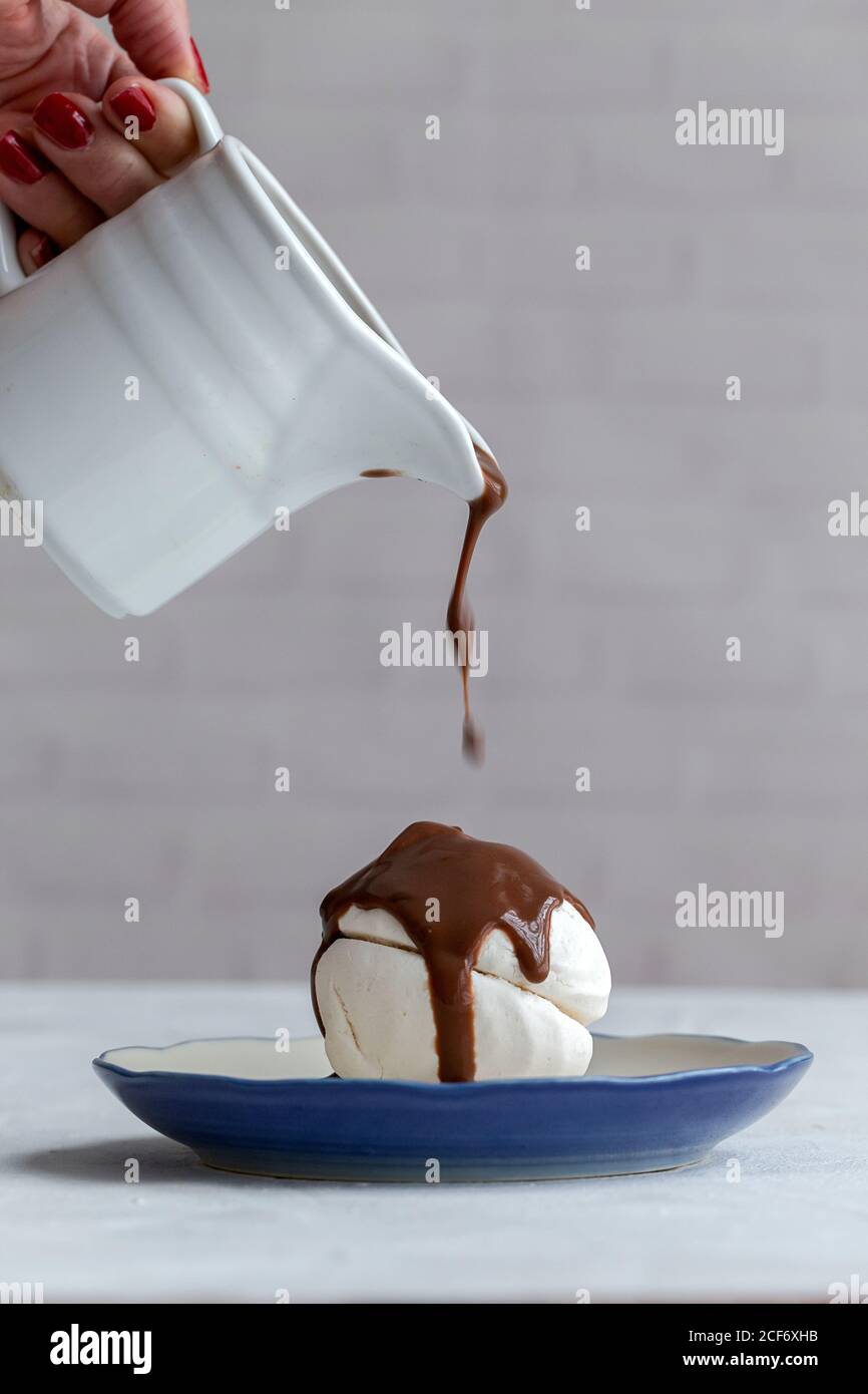 unrecognizable crop Woman hand with white jar pouring chocolate syrup ...