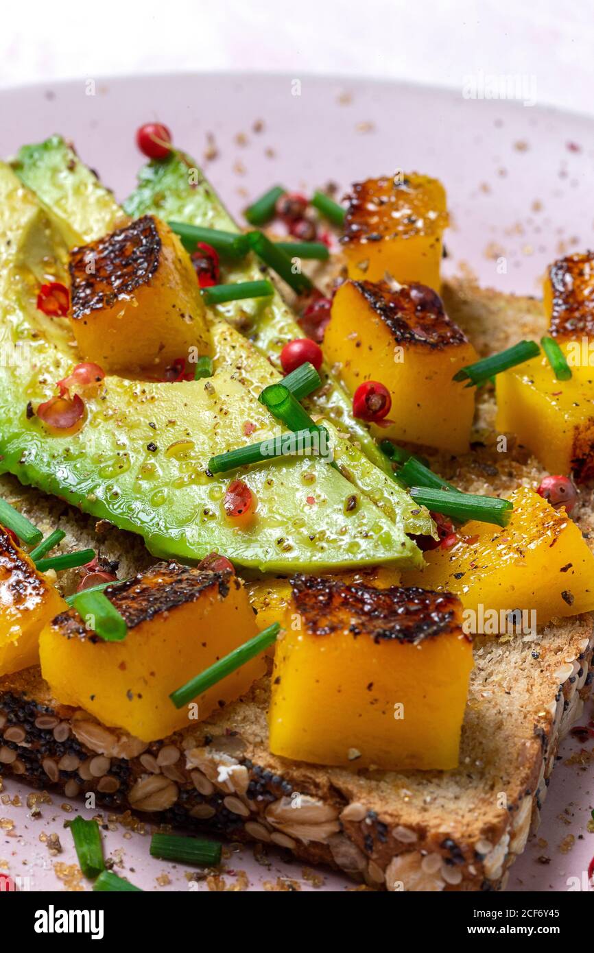 Homemade toasted bread with avocado, mango and aromatic herbs on pink ...