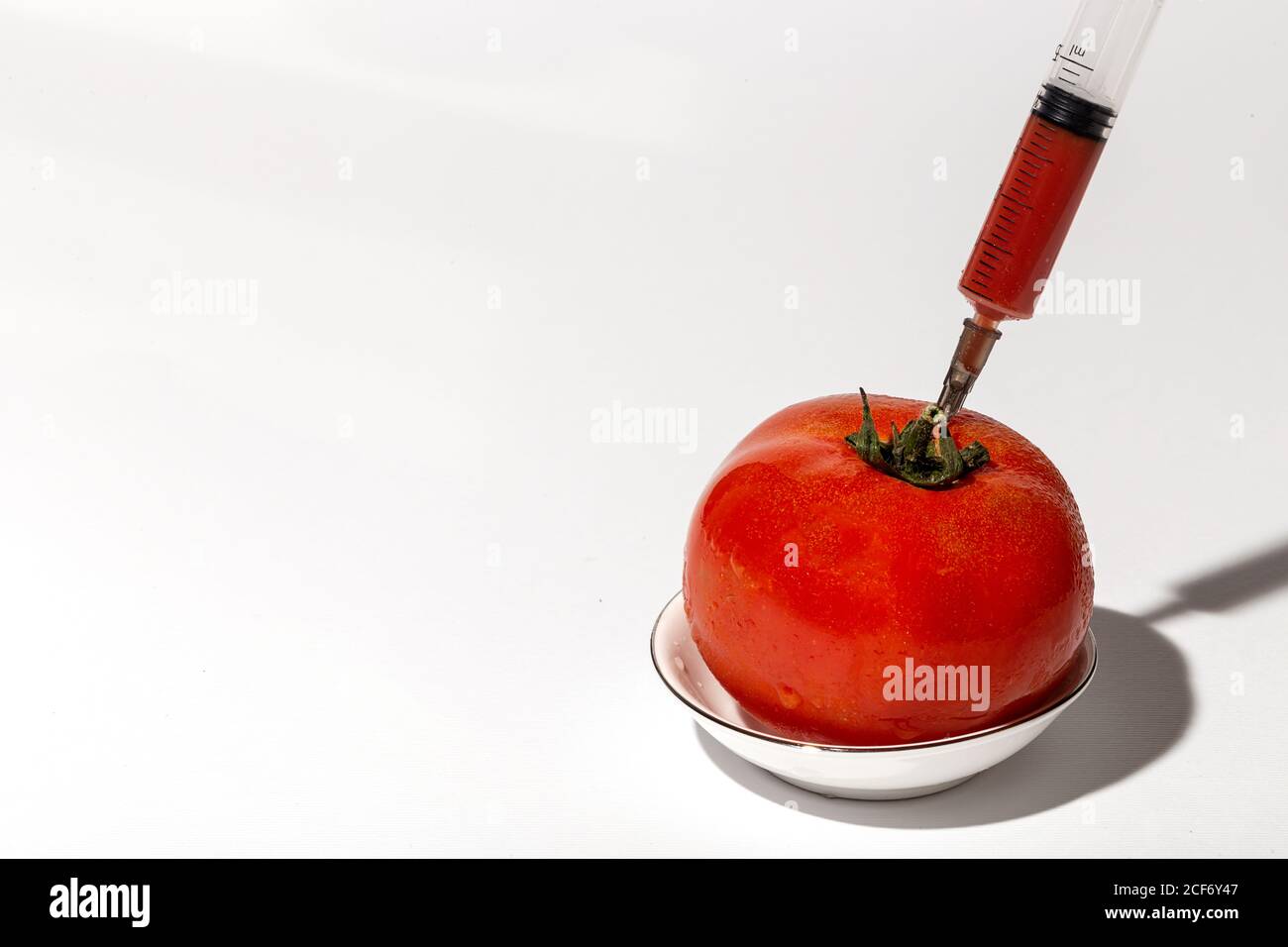 Injection of red pigment and pesticides into ripe fresh tomato against ...