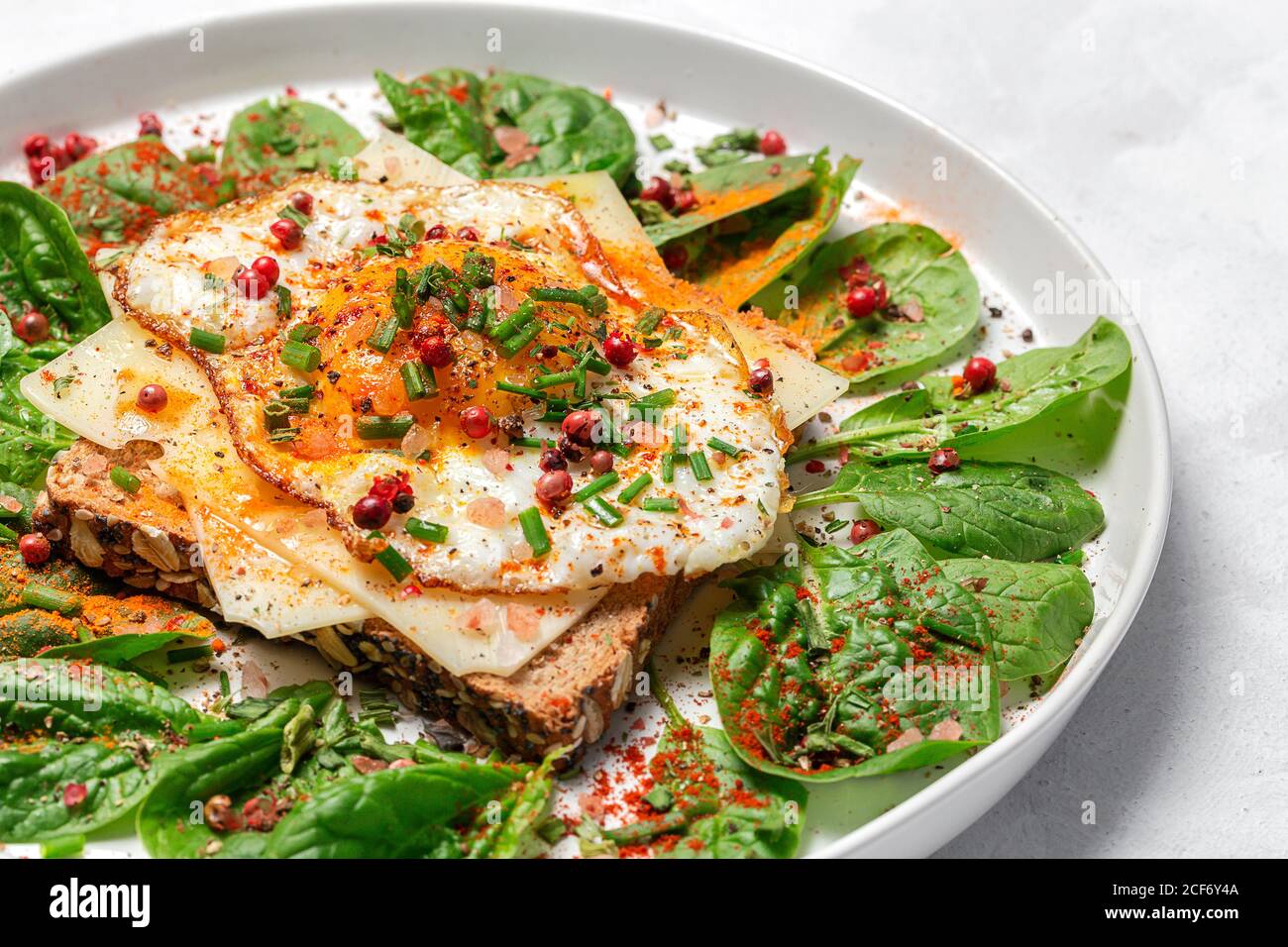 Homemade toasted bread with fried egg, spinach and aromatic herbs on ...