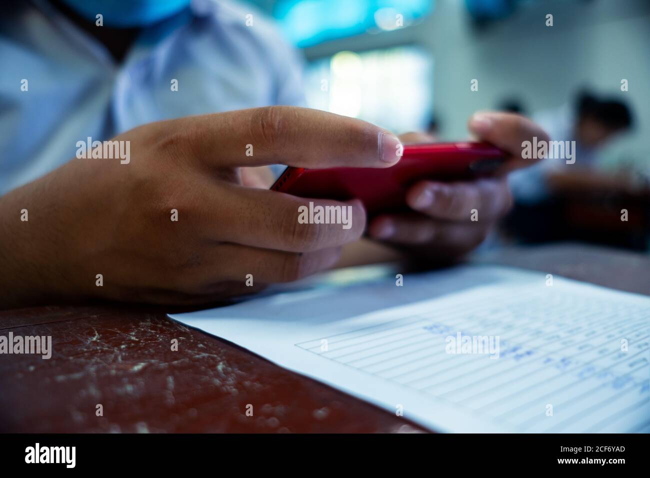 Students using smartphone and doing exam answer sheets exercises in ...