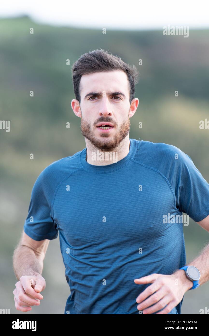 Bearded male athlete in active wear running during empty sandy beach ...