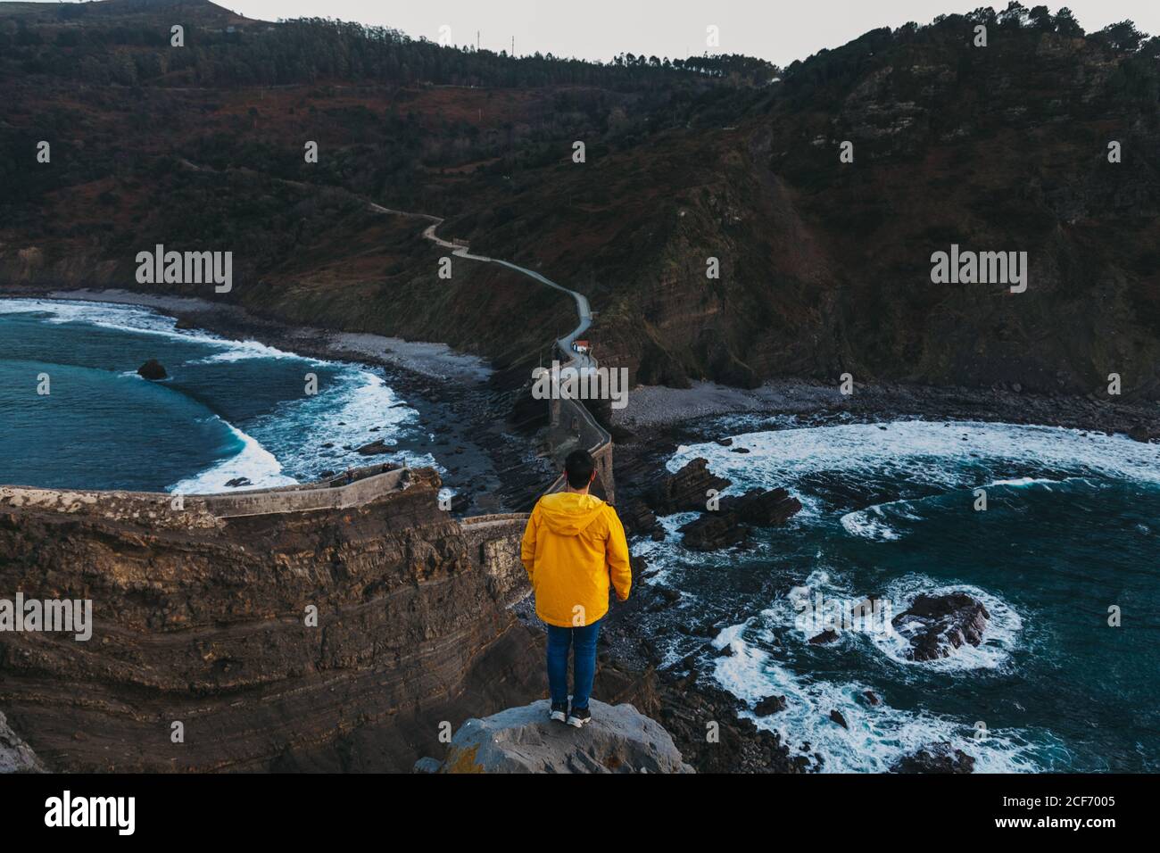 From above back view of faceless man in vivid yellow jacket and denim ...