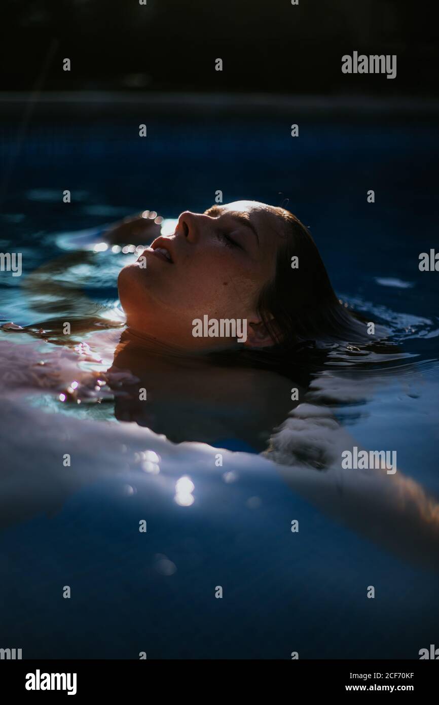 Side view of face above water surface of resting tranquil Woman with ...