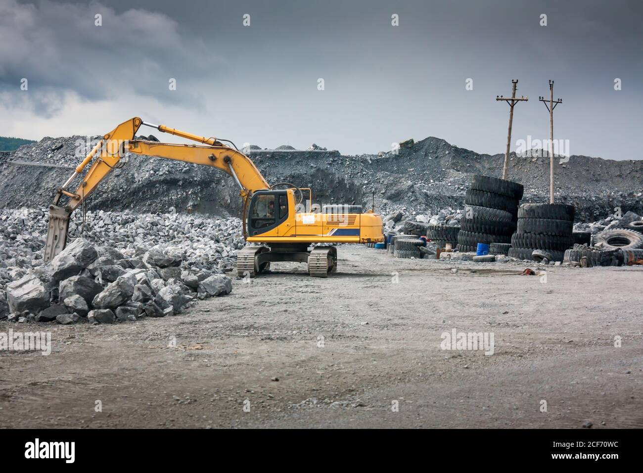 Heavy excavator with shovel standing on hill with rocks Stock Photo - Alamy