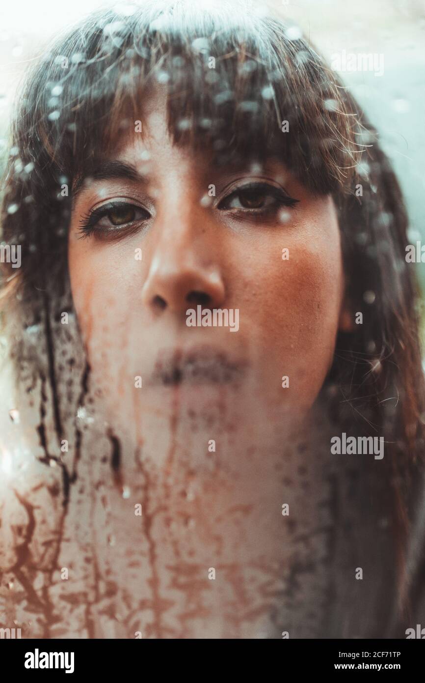 Beautiful female breathing on wet surface of transparent glass and ...