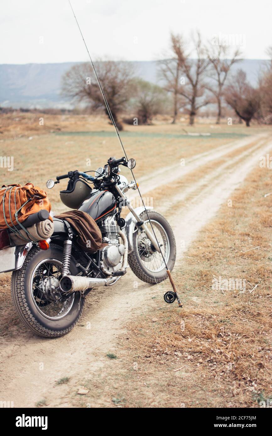 Fishing pole and motorcycle located on narrow countryside road in dry ...