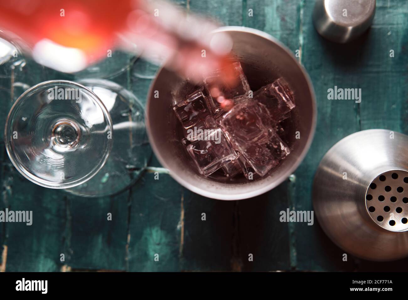 From above process of pouring red alcohol drink from bottle into shaker ...