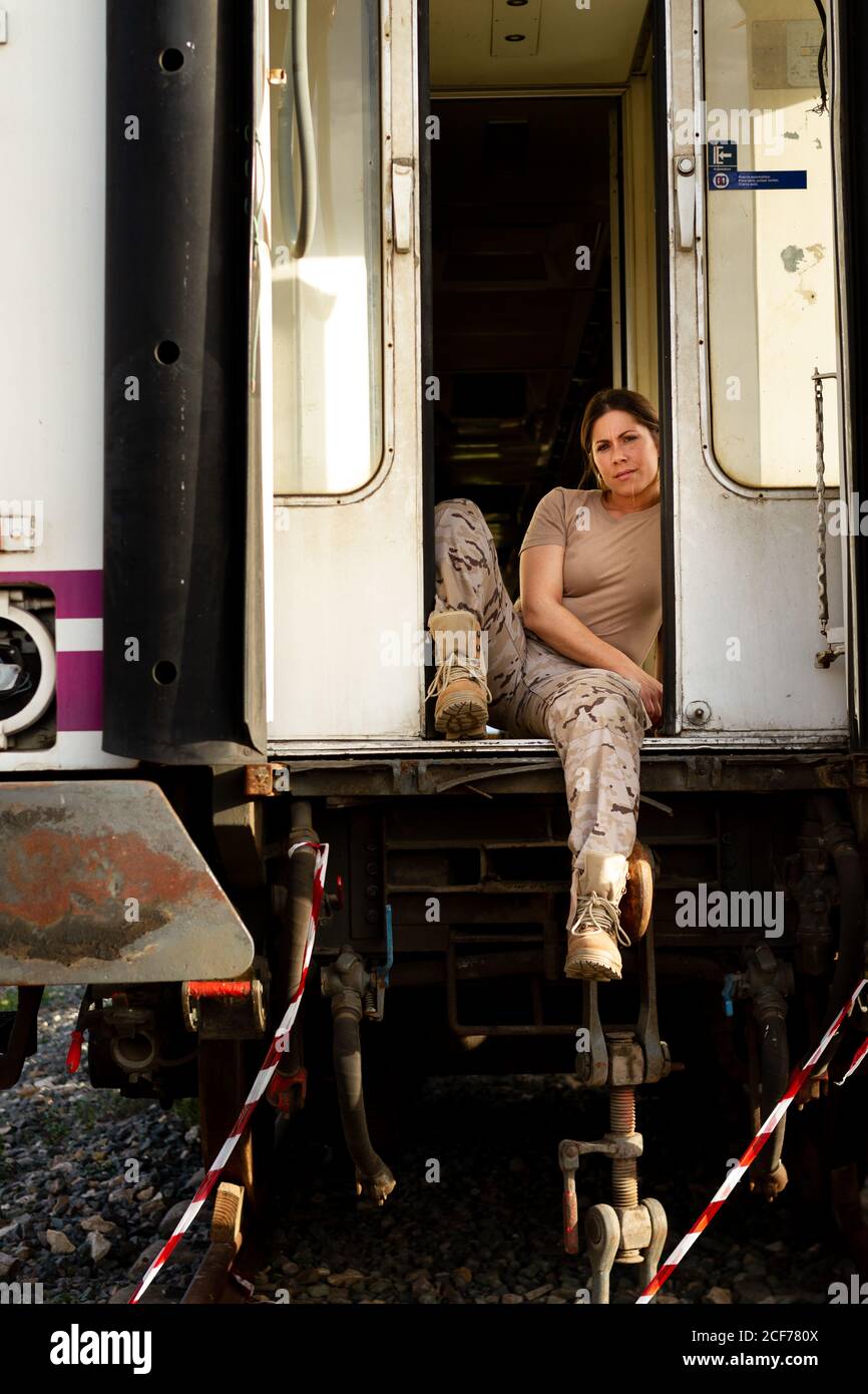 Strong female soldier looking at camera and thinking while sitting in ...