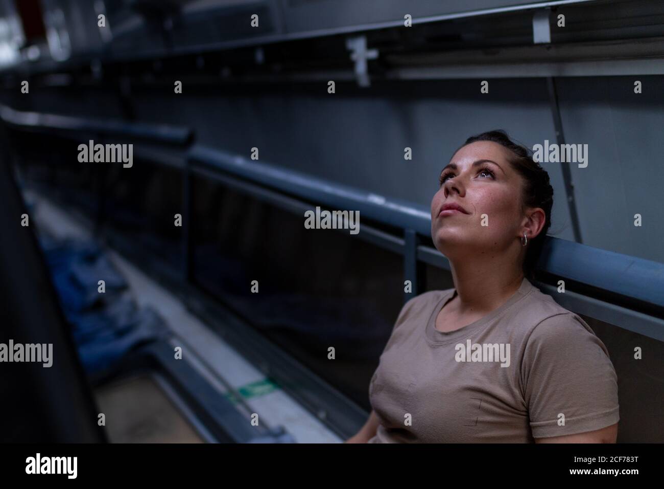Attractive female soldier looking up while sitting inside modern ...