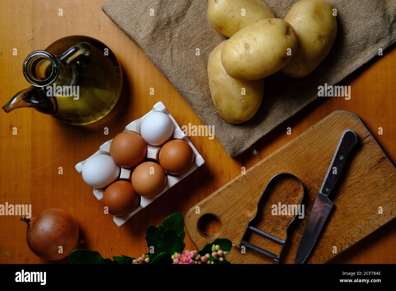 Top view of raw potatoes on table with olive oil in jar eggs onion ...