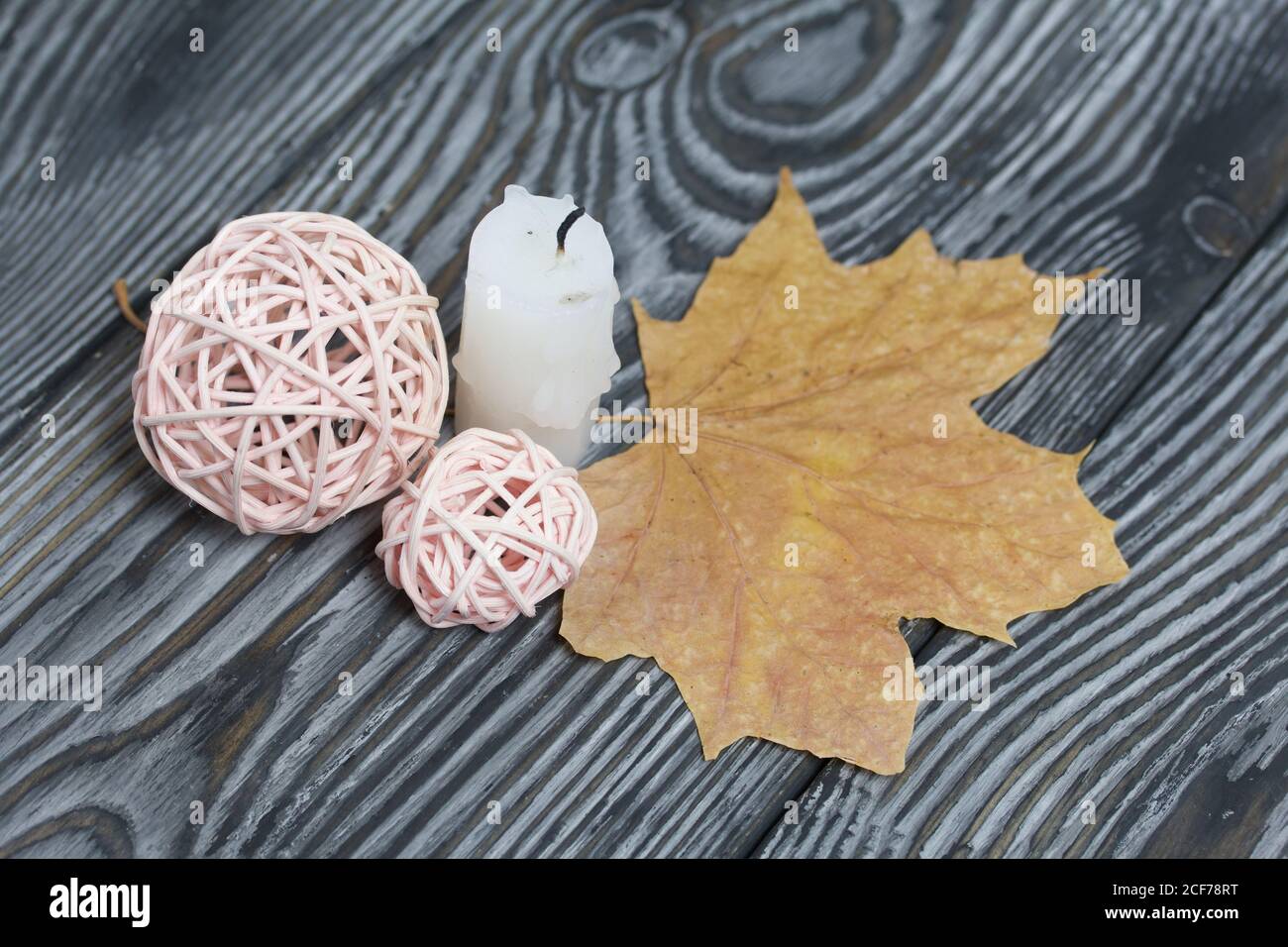 Candle stub on brushed pine boards. Nearby are dried maple leaves and ...