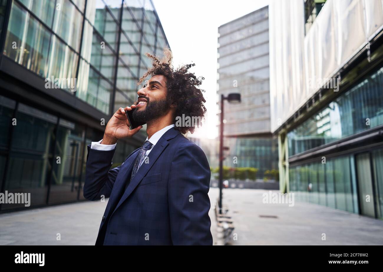 Curly ethnic man smiling at street Stock Photo - Alamy