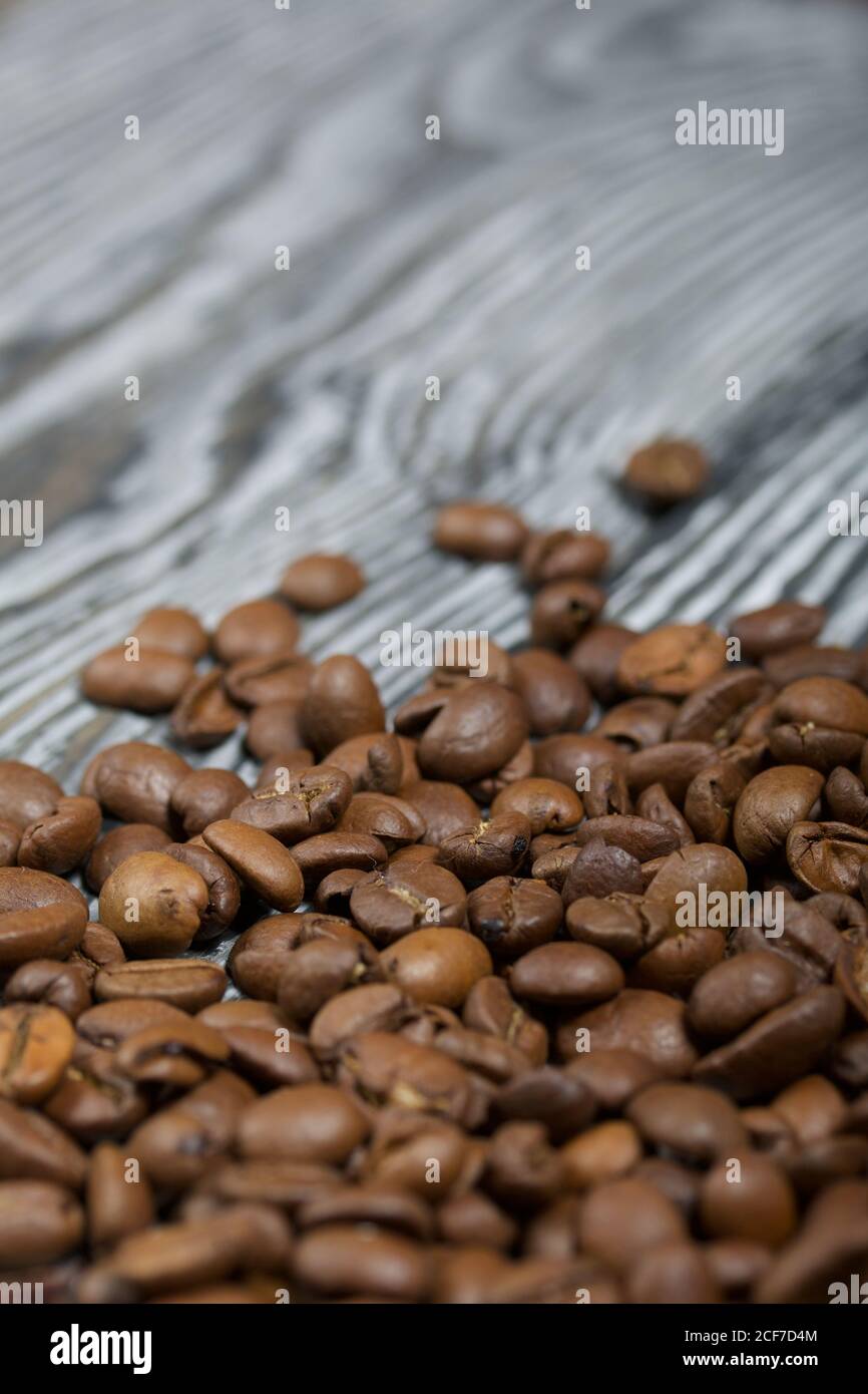 Coffee beans on a black-and-white brushed pine plank surface. Close-up ...